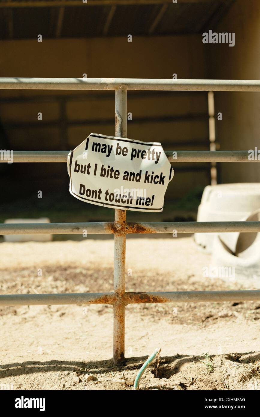 Sign on a fence warning about a biting, kicking animal Stock Photo - Alamy