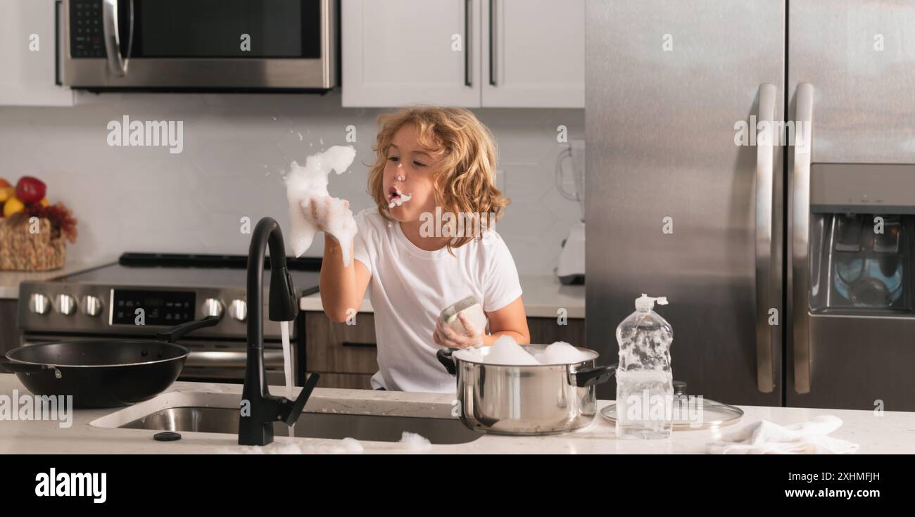 Home chores. Kid in kitchen cleaning plates. Cute boy washing dishes in ...