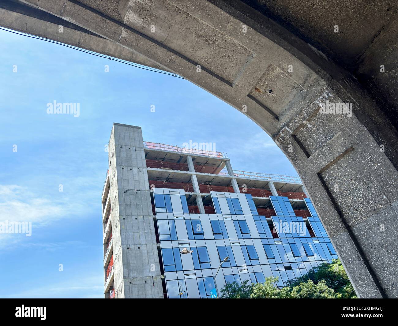 Modern glass building under construction framed by a concrete arch Stock Photo - Alamy