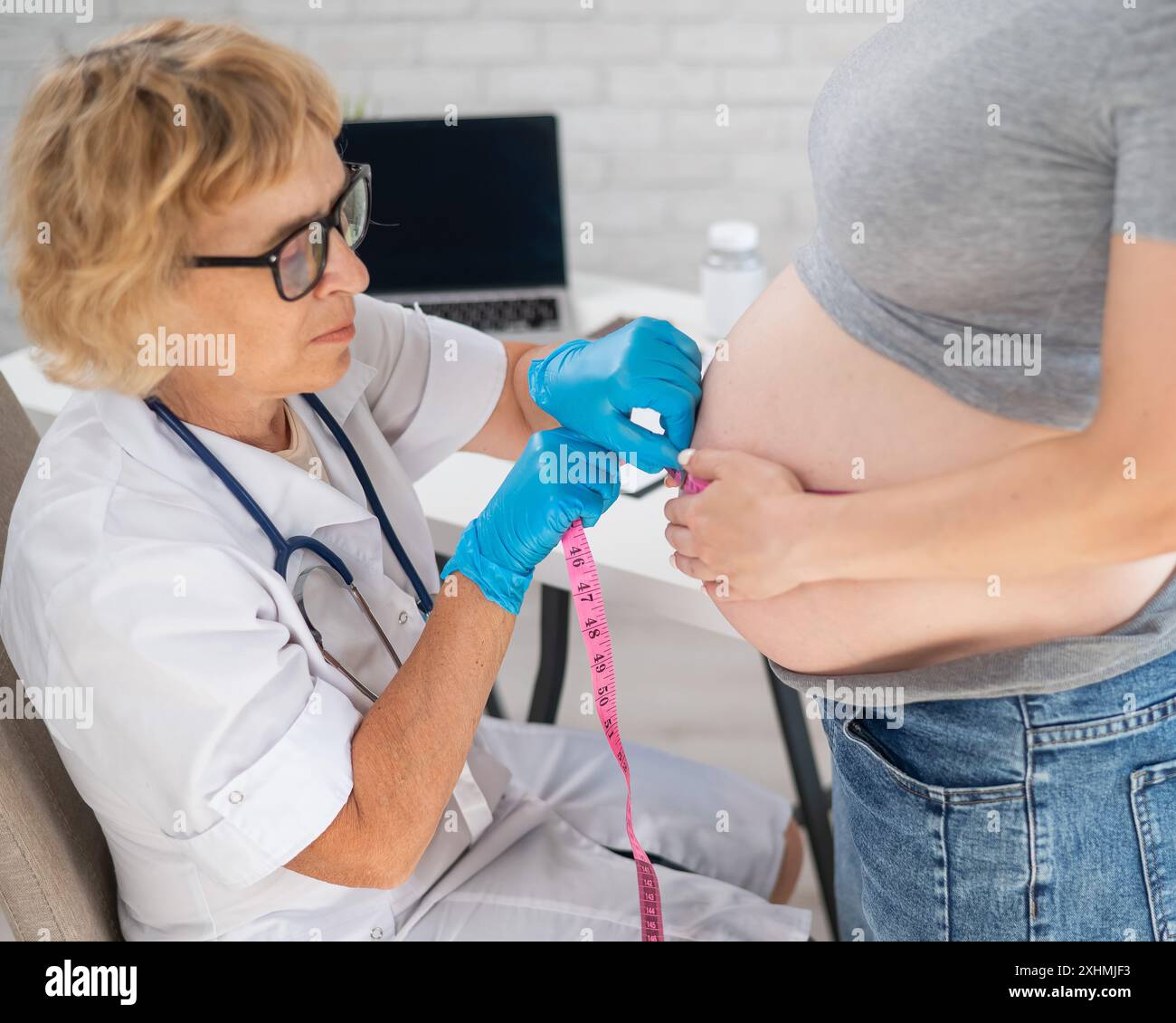 Doctor measuring the volume of a pregnant woman's abdomen using a ...