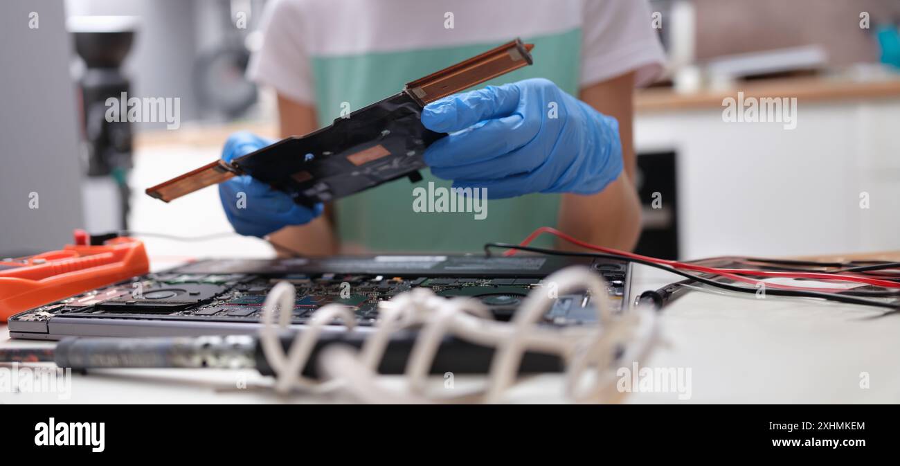 Close-up of tech fixes motherboard of laptop in service center. Laptop disassembling parts and ...