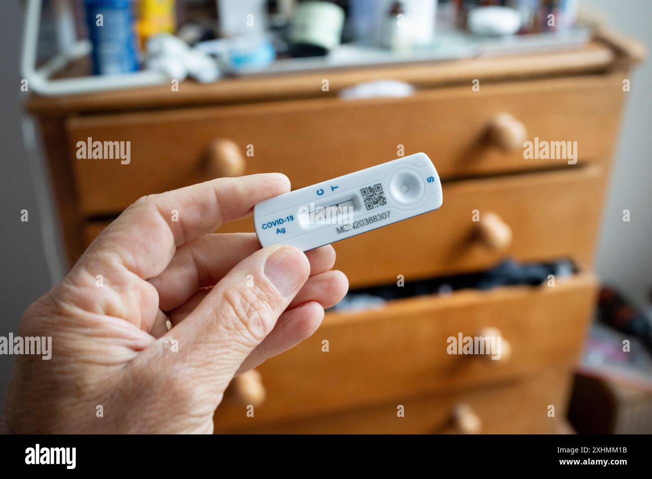 A detail of a hand holding a Covid lateral flow test that shows a ...
