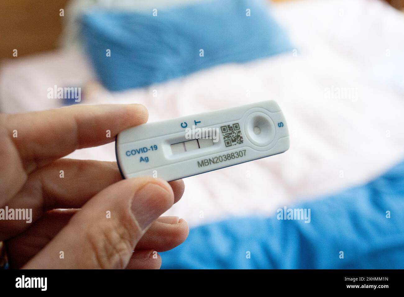 A detail of a hand holding a Covid lateral flow test that shows a ...