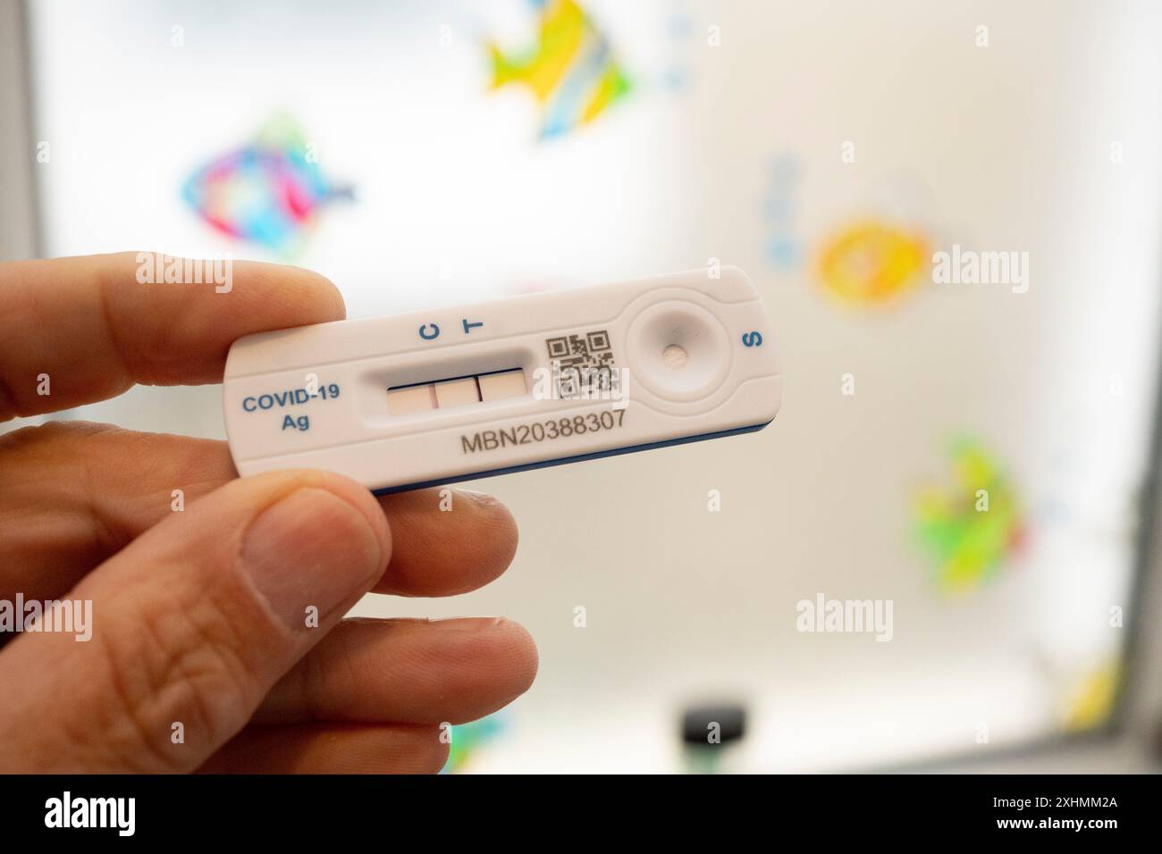 A detail of a hand holding a Covid lateral flow test that shows a ...