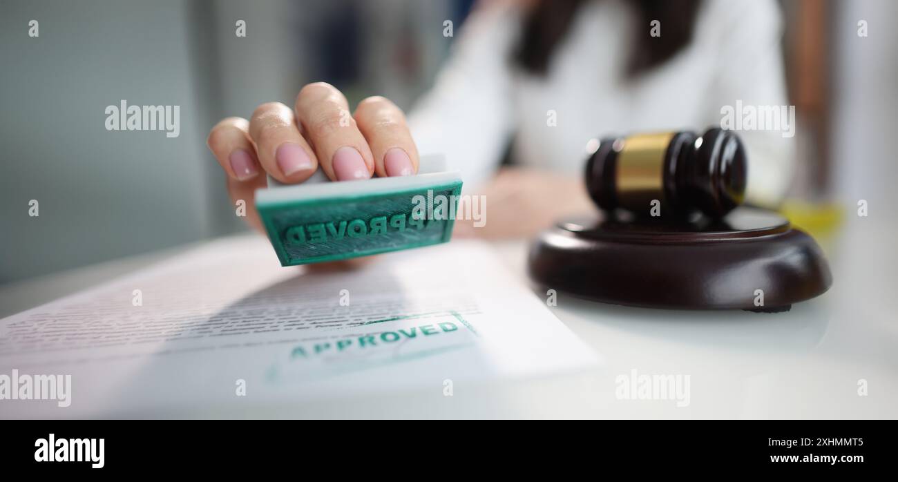 Female hand holding approved stamp, judge gavel Stock Photo - Alamy