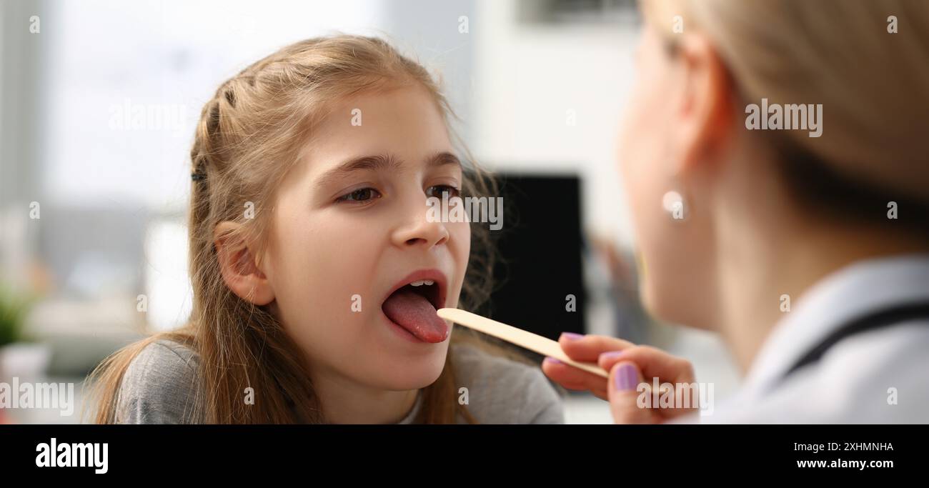 Portrait of pediatrician checking girls hurting throat with stick ...