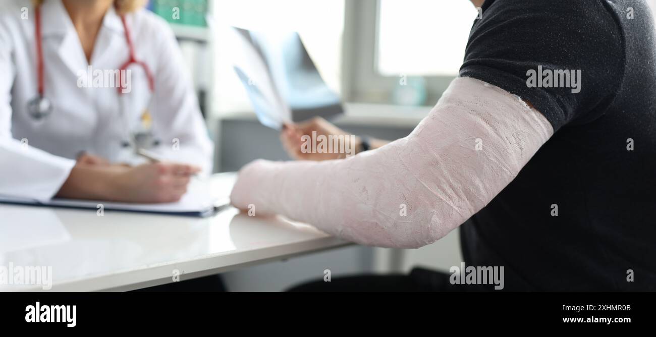 Close-up of man with broken arm at doctor appointment. Doctor at ...