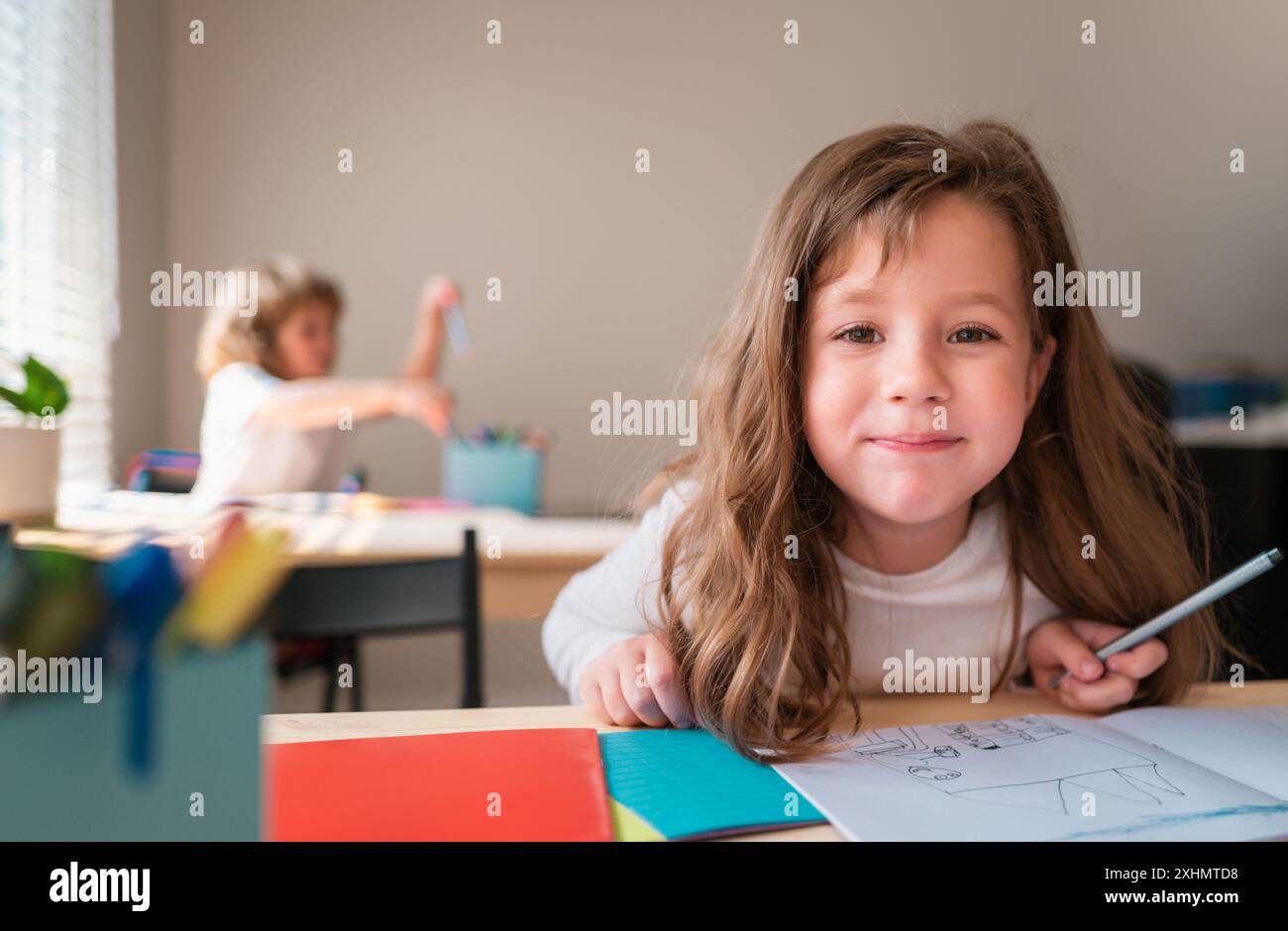 Funny happy schoolgirl writing notes in class. Kids in classroom at ...
