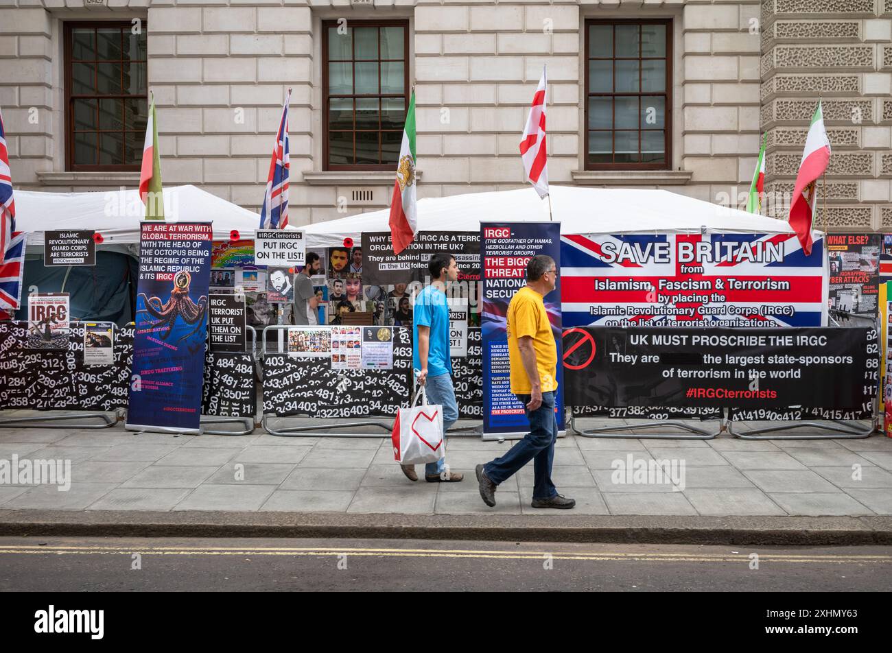 London / UK - Jul 11 2024: Two men walk past posters and slogans at the ...