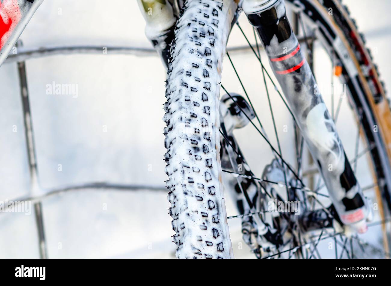 Close-up of bicycle wheel at car wash. Washing the bicycle with jet of ...