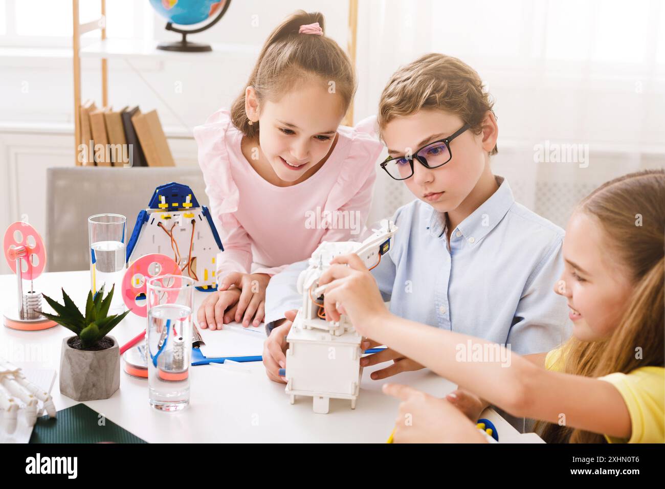 Three Children Working on Science Project in Classroom Stock Photo - Alamy