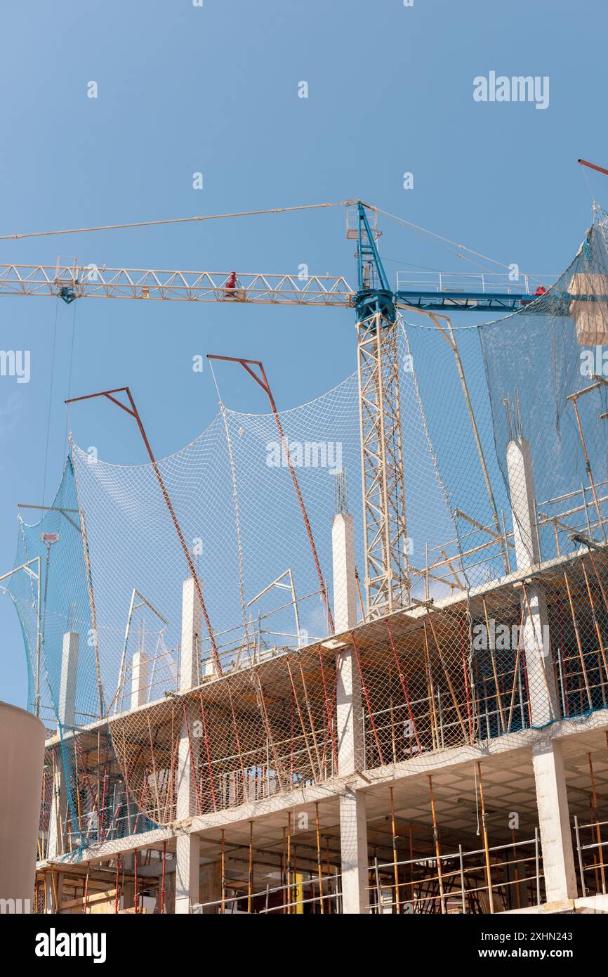 New building construction process. Safety nets, structural beams highlight ongoing work. Multi ...