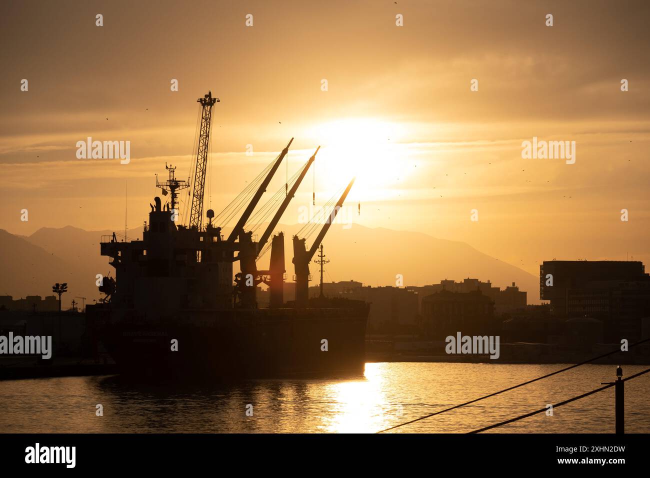 Sundown Cargo Ship Silhouette at Harbor With Faint Mountainous Backdrop ...