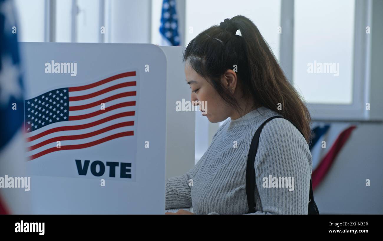 Multi ethnic American citizens come to vote in booth in polling station ...