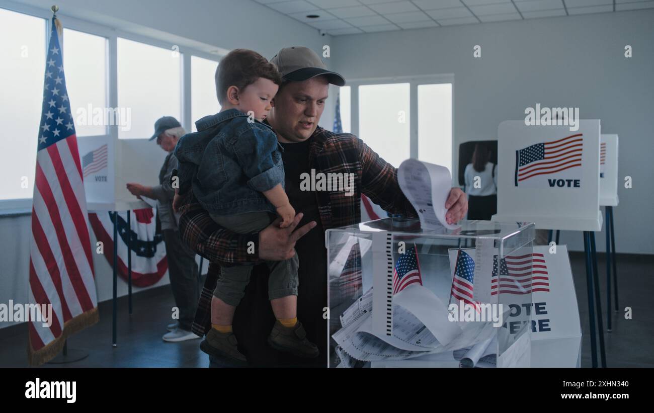 African American man and Caucasian man with child put ballots in box ...