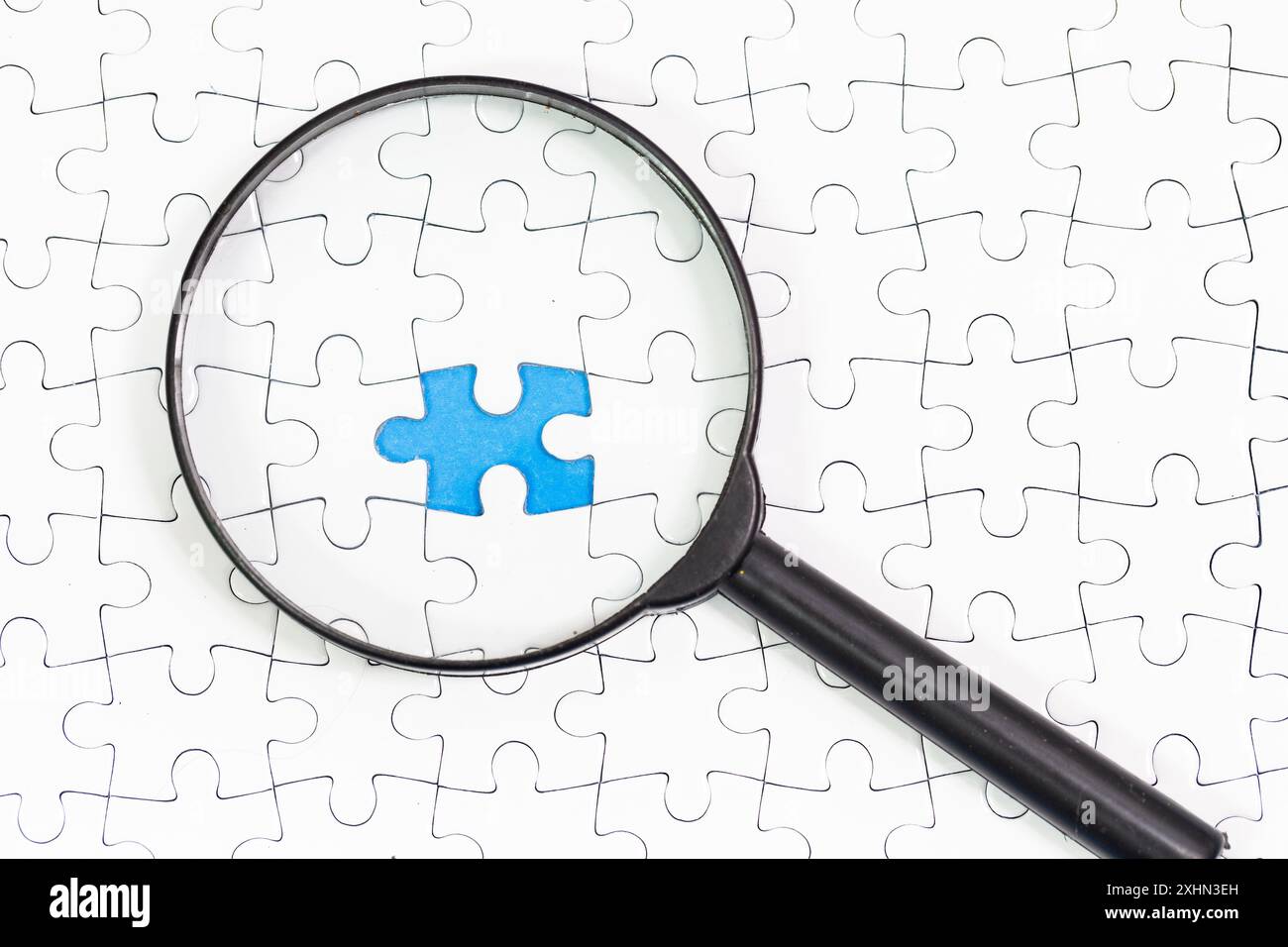 A puzzle with one piece missing and a magnifying glass. business and ...