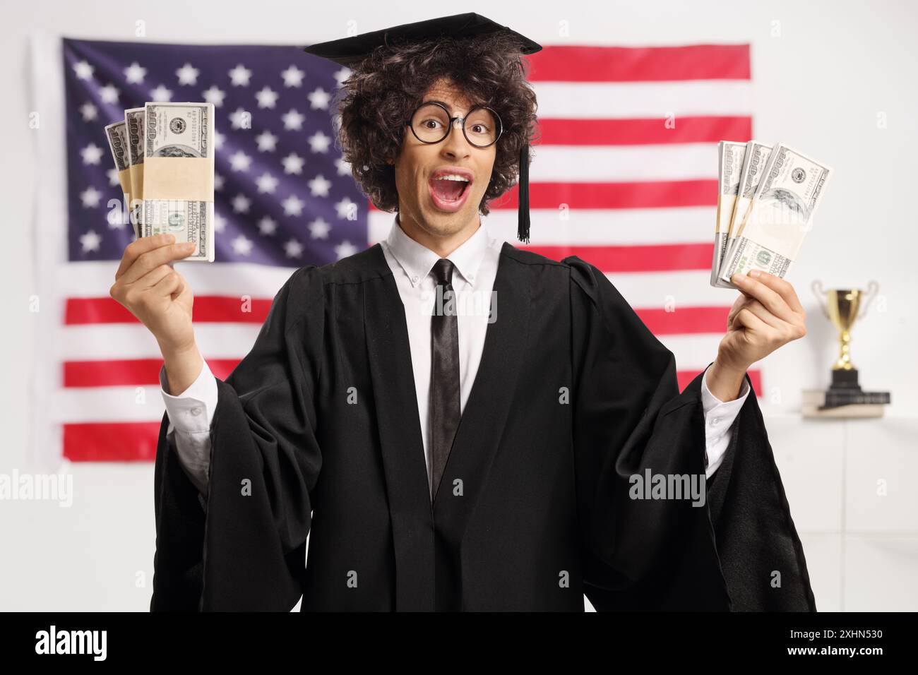 Excited graduate student in a gown holding money in front of the USA ...