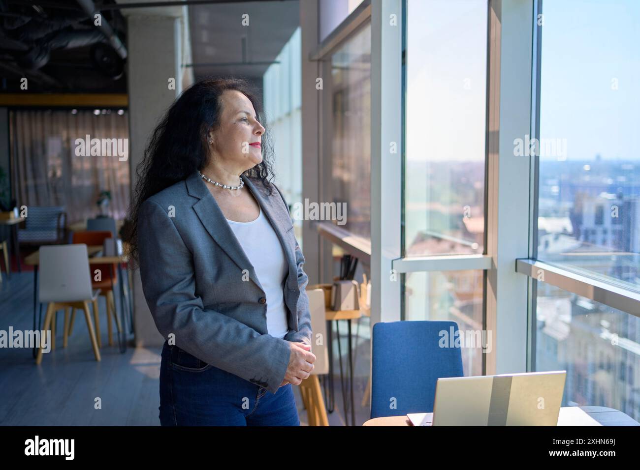 57-year-old woman works on a laptop in a modern office workspace Stock ...