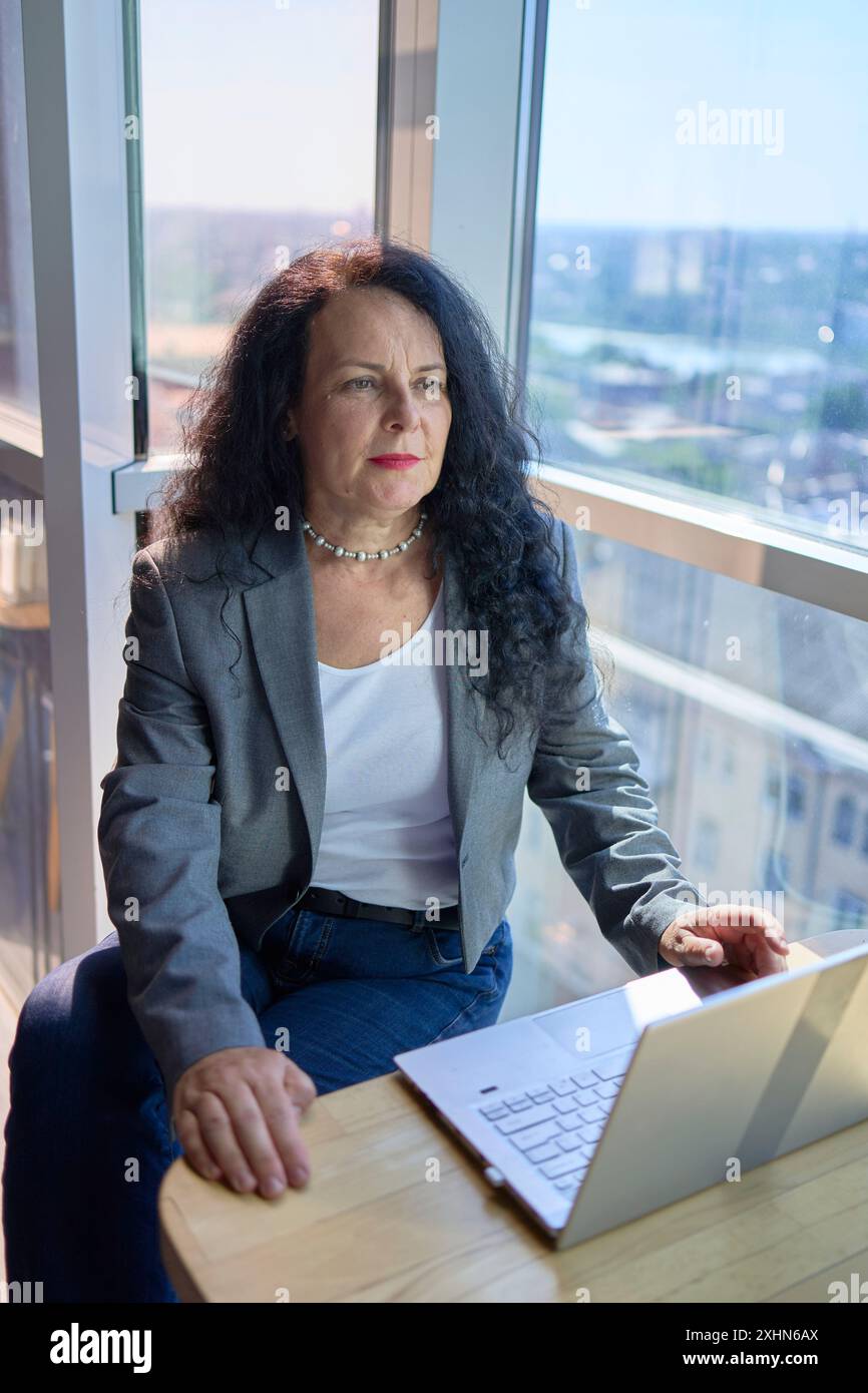 57-year-old woman works on a laptop in a modern office workspace Stock Photo - Alamy