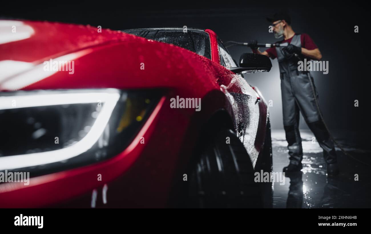 Car Wash Expert Using Water Pressure Washer to Clean a Red Modern ...