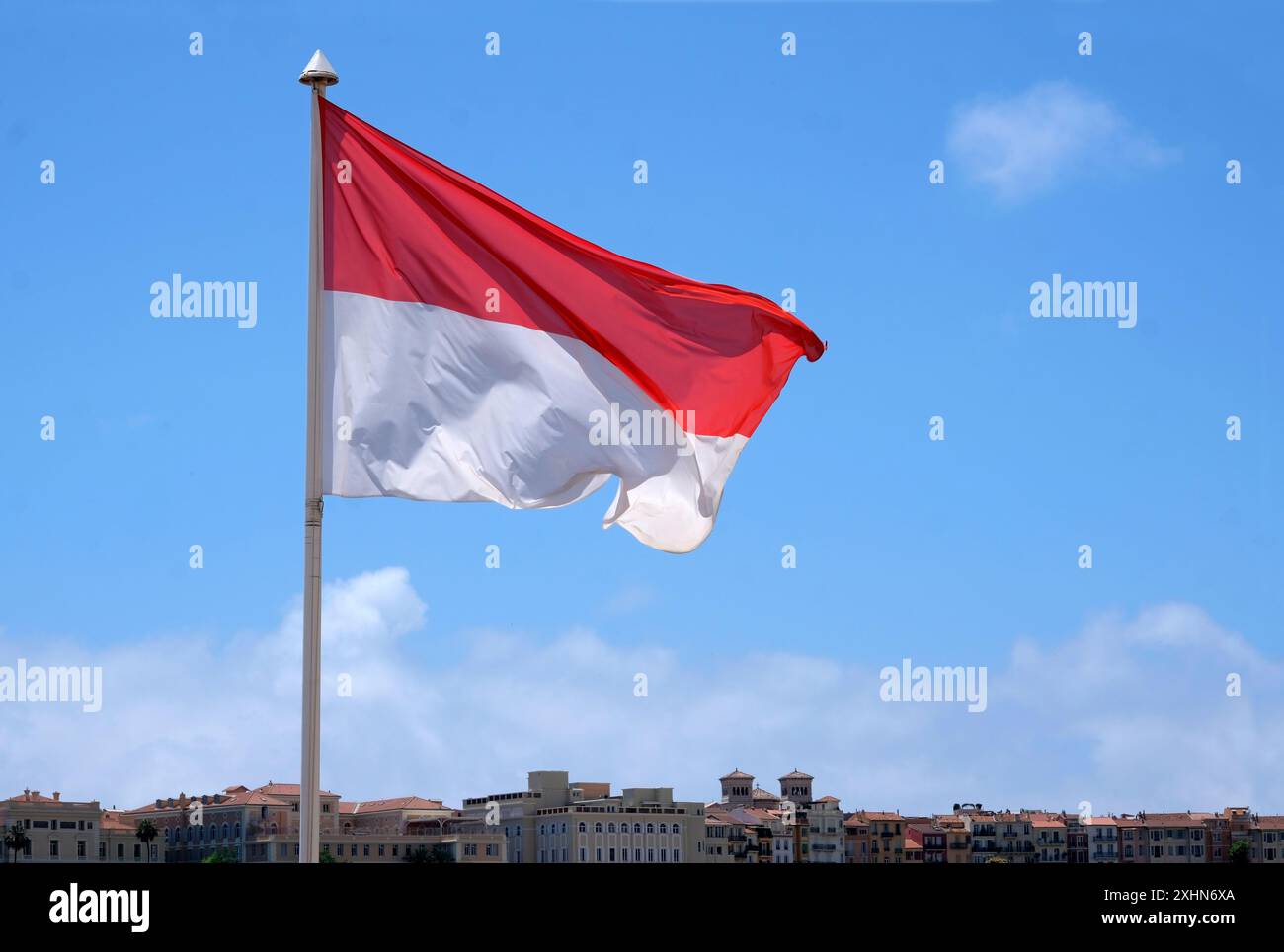 The flag of Monaco waving in the wind in front of a blue sky Stock ...