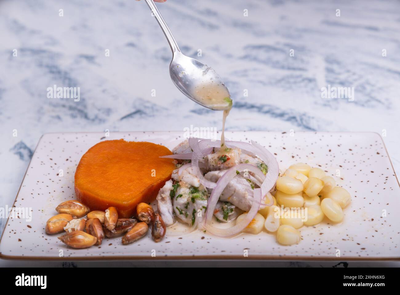 Spoon pouring the juice of the traditional Peruvian dish called Ceviche ...