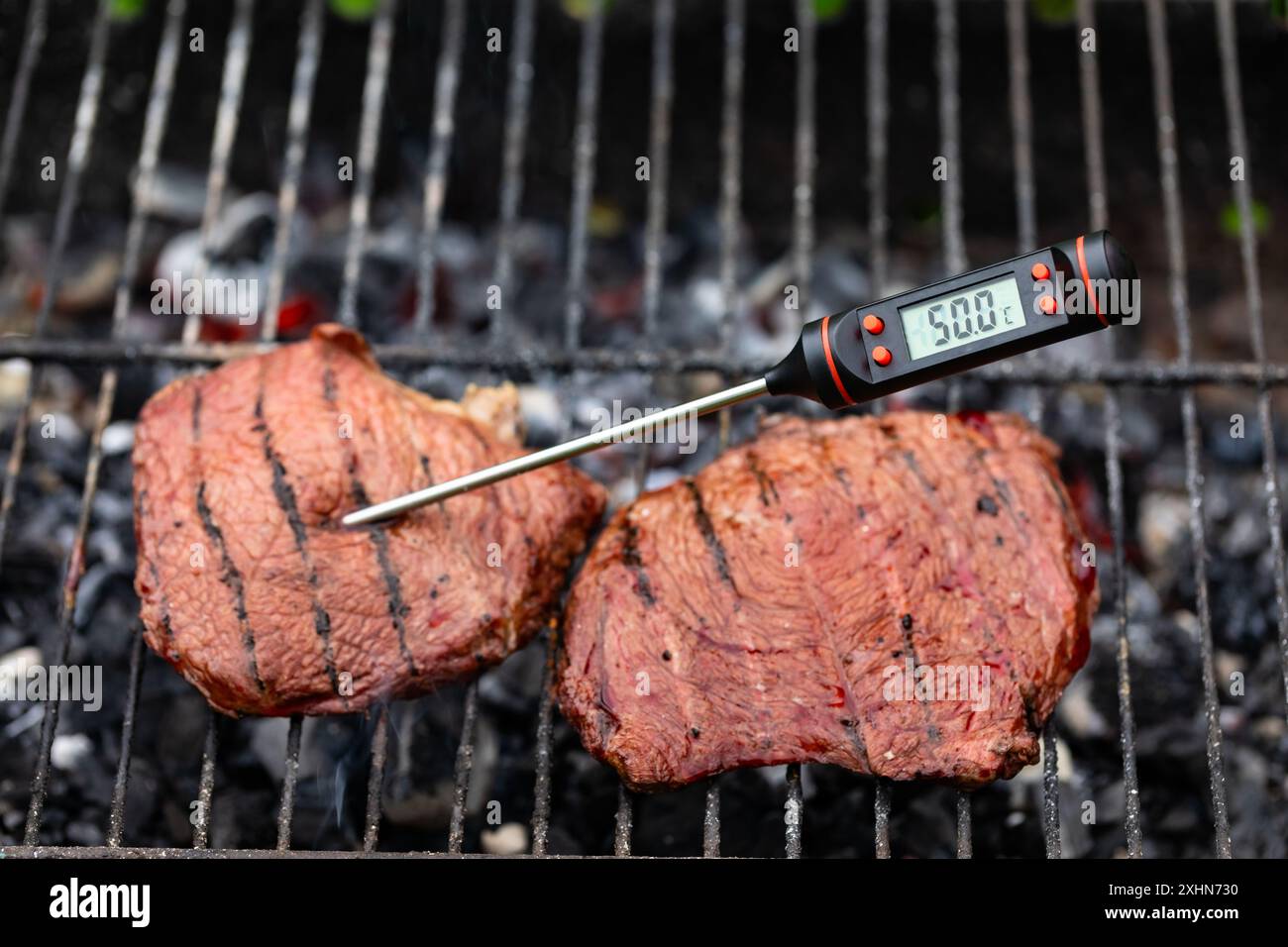 Close-up shot of digital meat thermometer inside grilled steak on ...