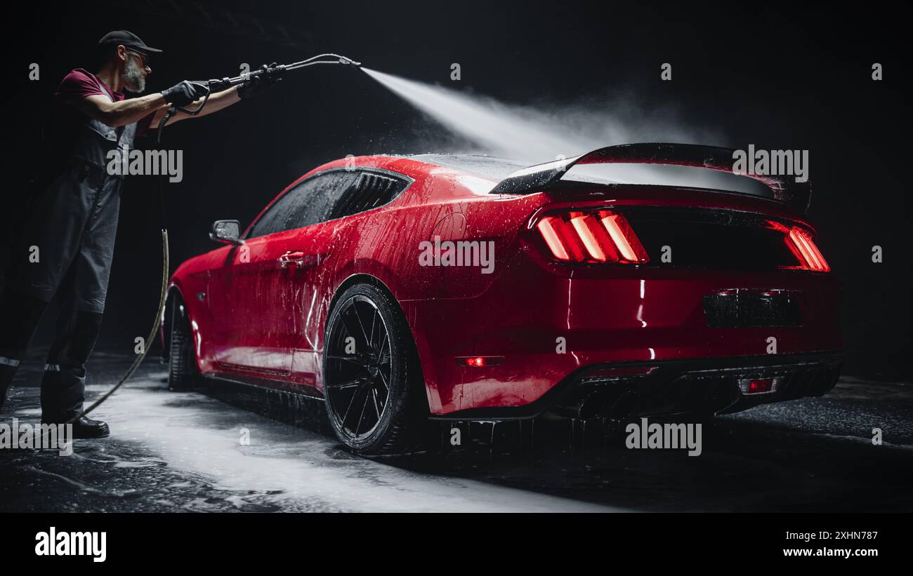 Car Wash Expert Using Water Pressure Washer to Clean a Red Modern ...