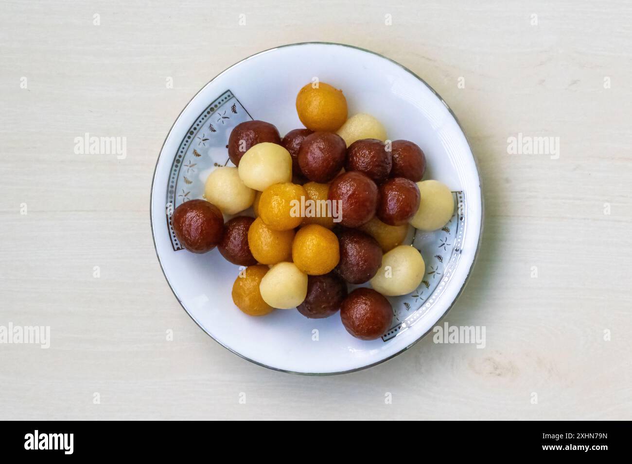 Delicious Bangladeshi sweets on a white plate on light wooden ...