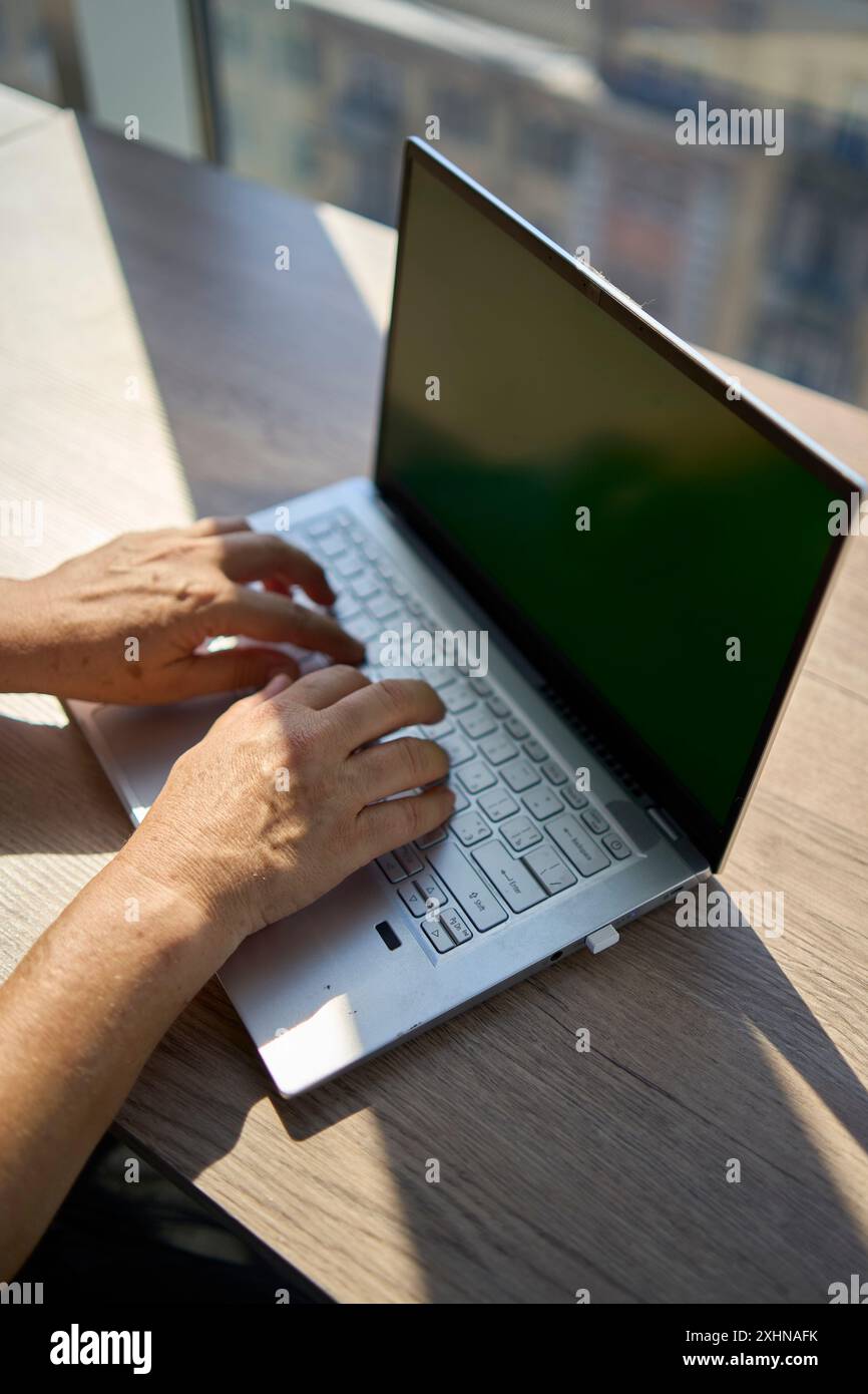 a 57-year-old woman works on a laptop in a modern office workspace ...