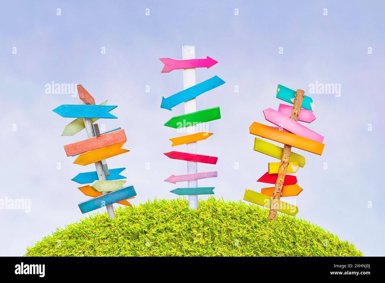 Round grass field with empty wooden direction signs in front of a blue ...
