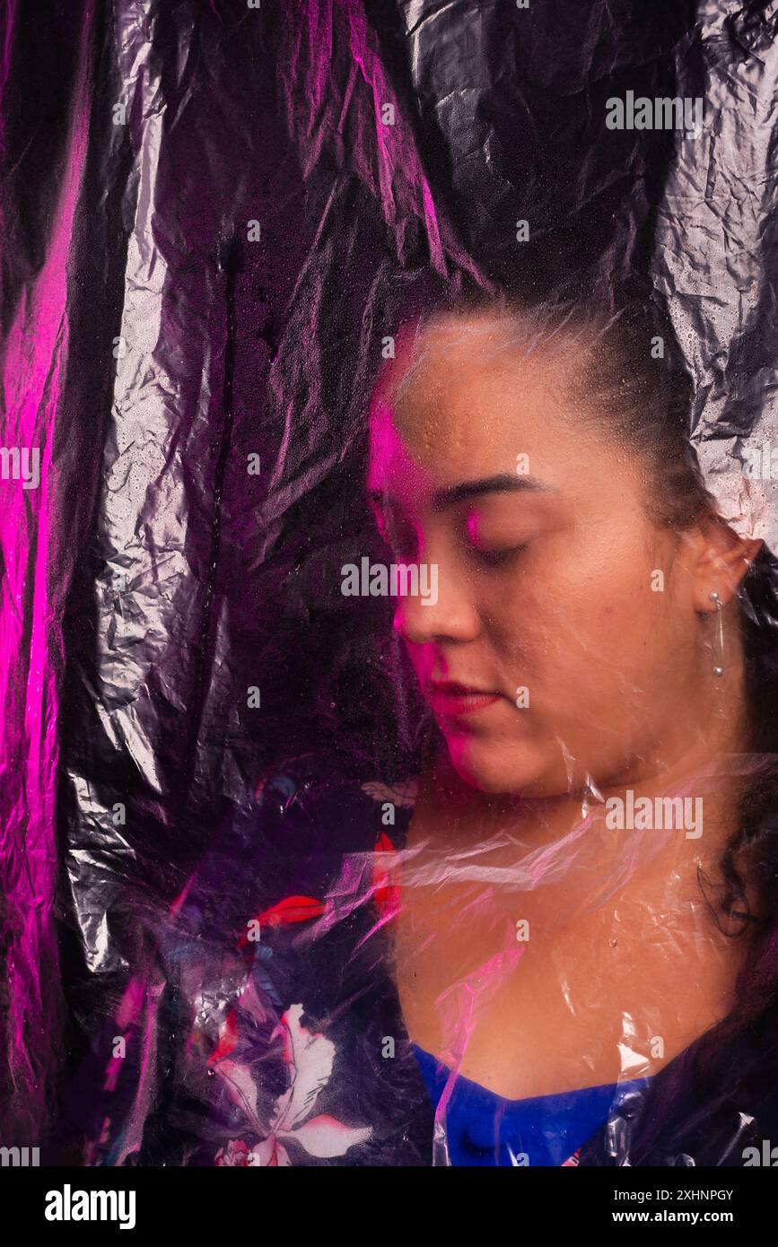 Beautiful woman behind transparent plastic posing. Photo in studio ...