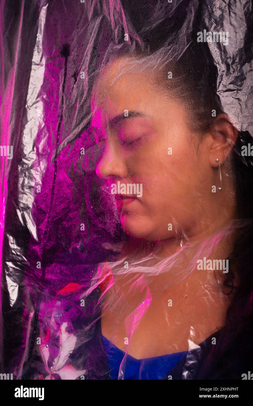Beautiful woman behind transparent plastic posing. Photo in studio ...