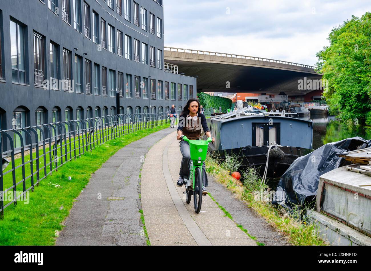 A cyclist cycles alongside The Grand Union Canal Paddington Arm with ...