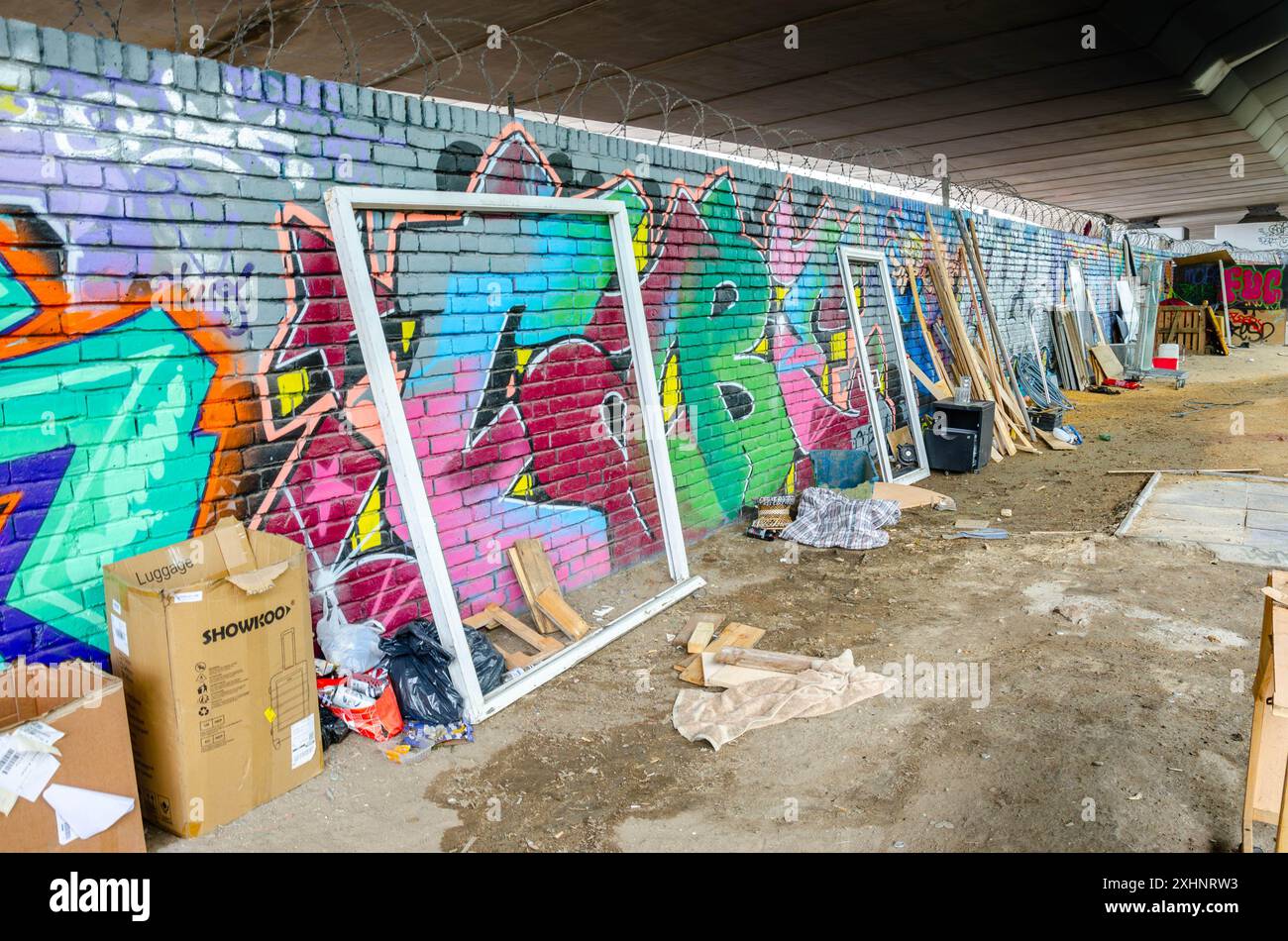 Rubbish and pieces of wood abandoned against a graffiti covered wall ...