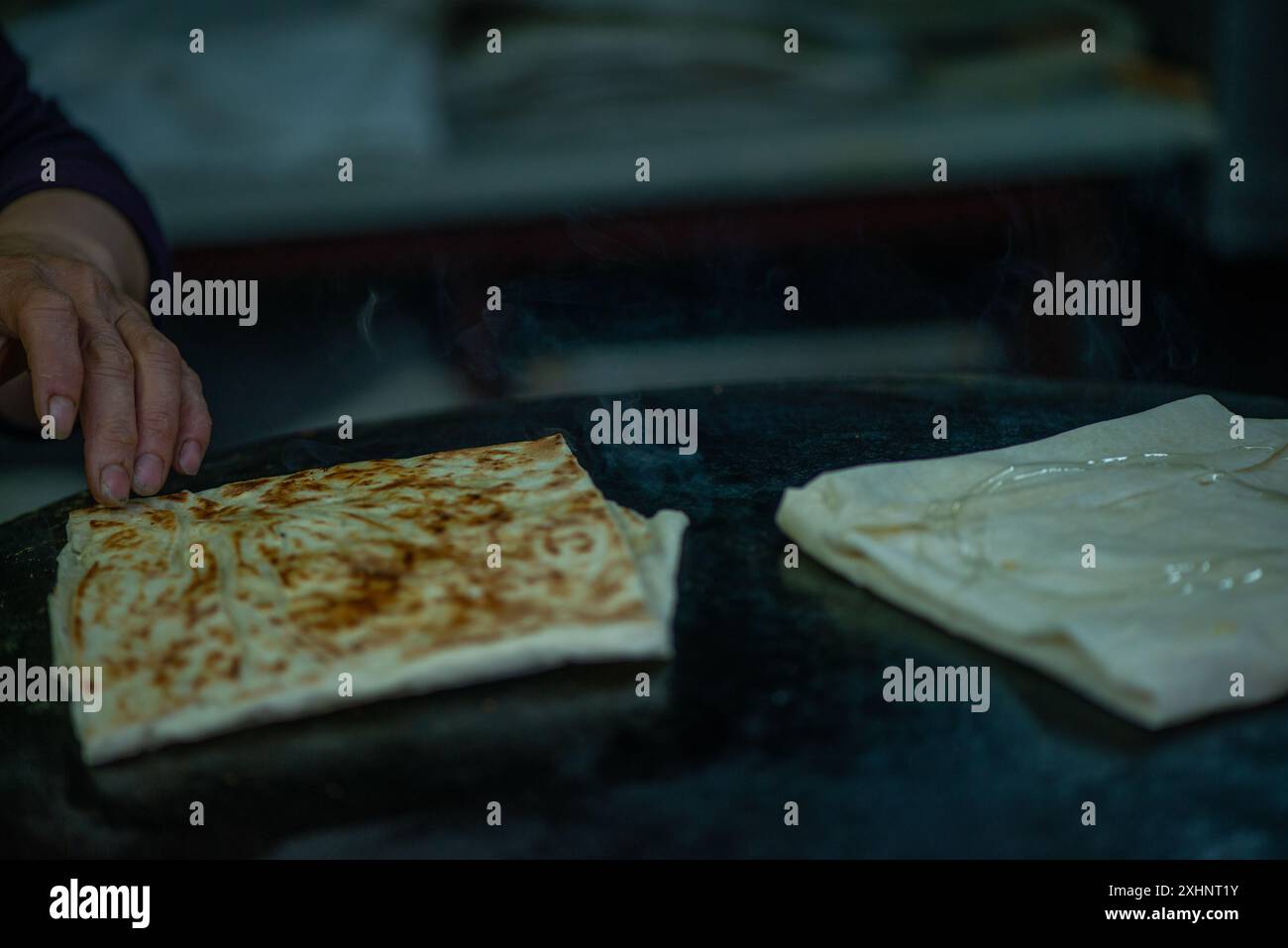 An elderly Turkish woman expertly rolls out dough for a traditional ...