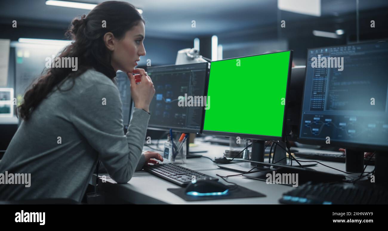 Female Software Developer Working on a Desktop Computer with Green Screen Mock Up Display ...