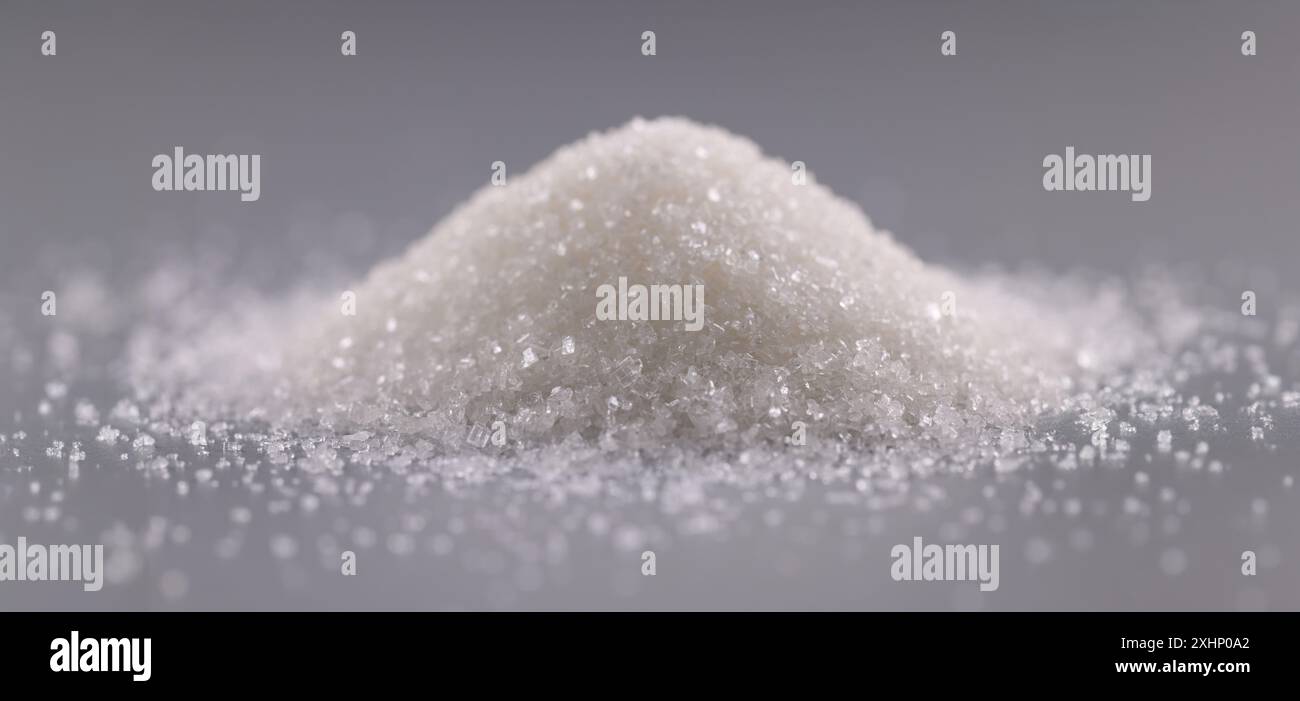 Pile of sugar crystals on grey surface, heap of sweet powder to add in ...