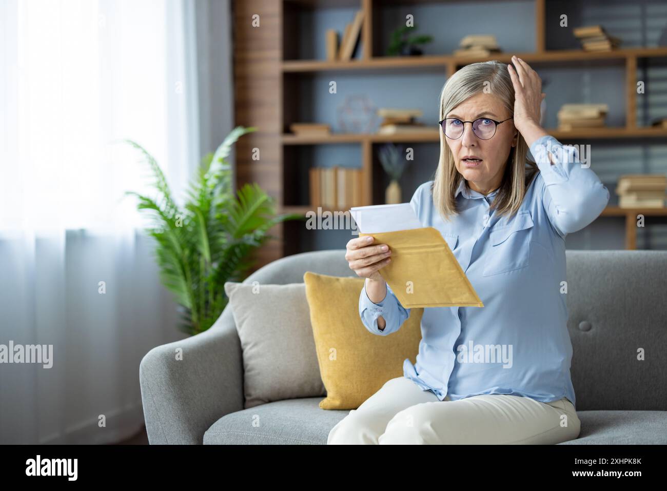 Shocked elderly woman receiving unexpected news while reading letter on ...