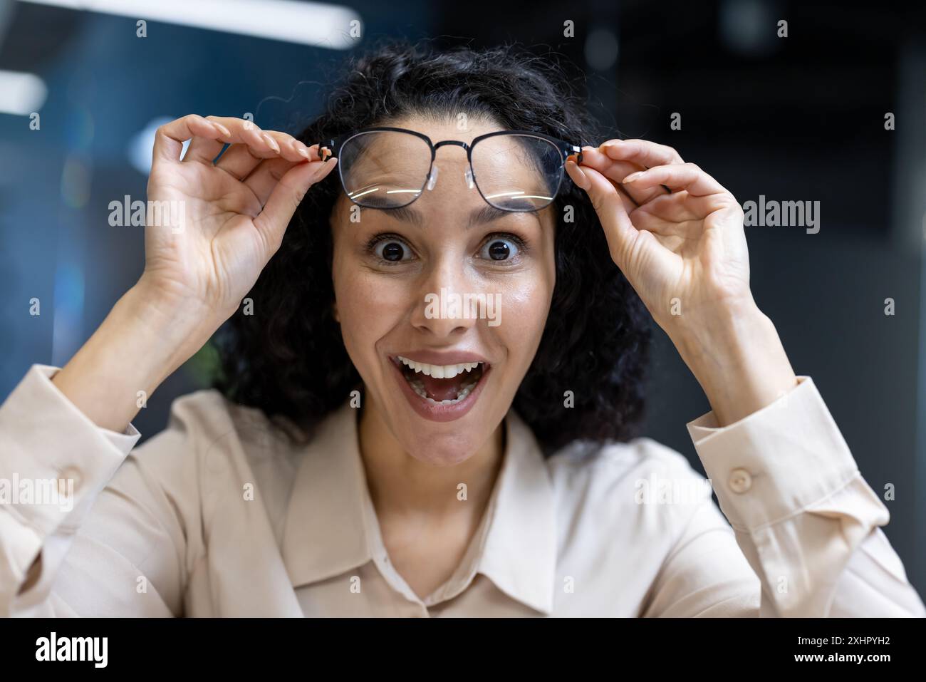Portrait of excited woman adjusting her glasses while looking at camera ...