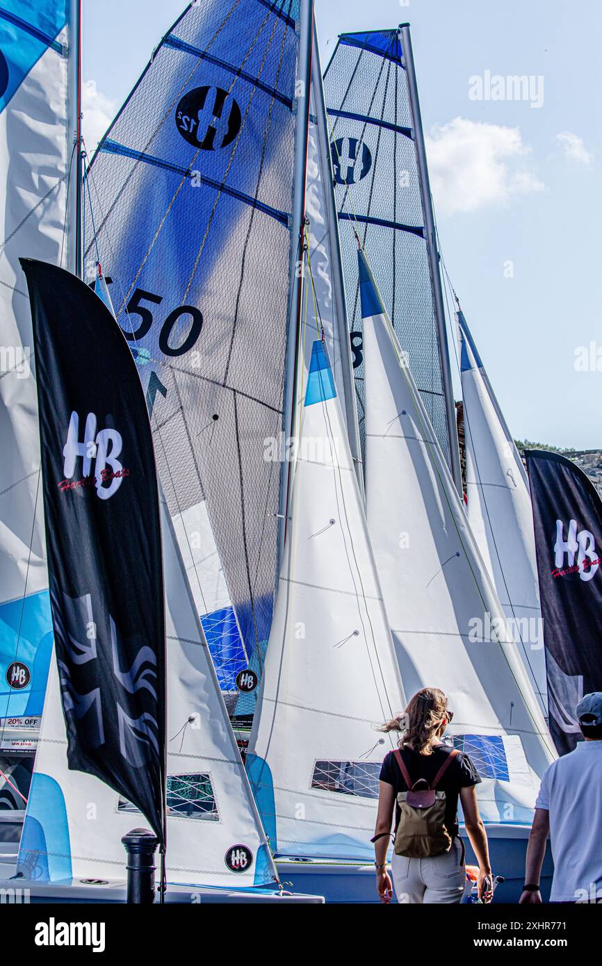 Two people 1 male, 1 female walking past boat sails blowing in the wind ...