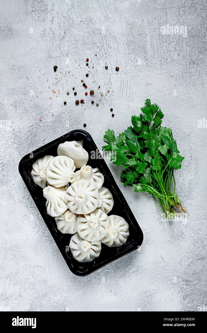 Freshly frozen, raw khinkali, in a black plastic container, top view ...
