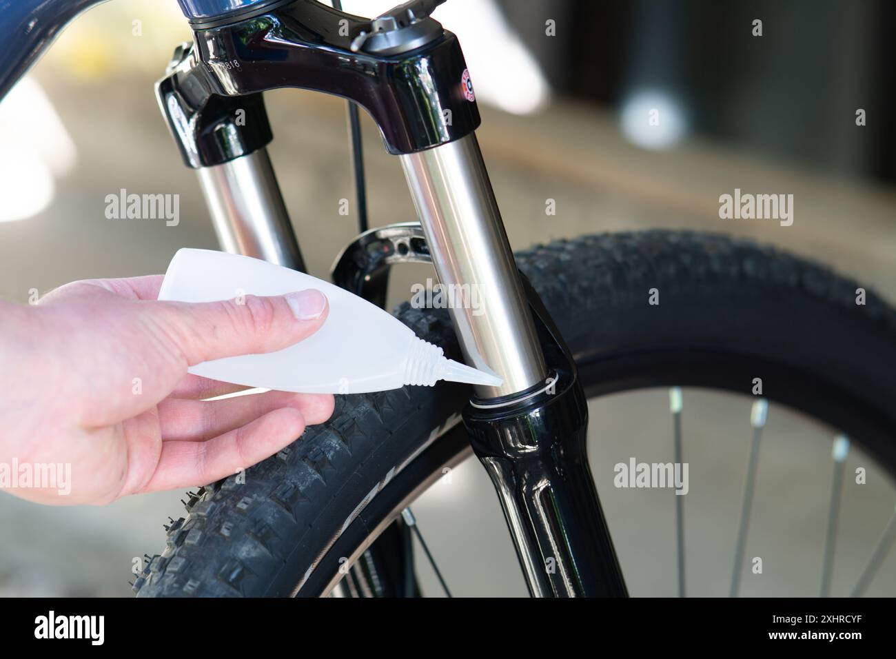 male hand putting oil on mountain bike suspension fork, lubricating ...
