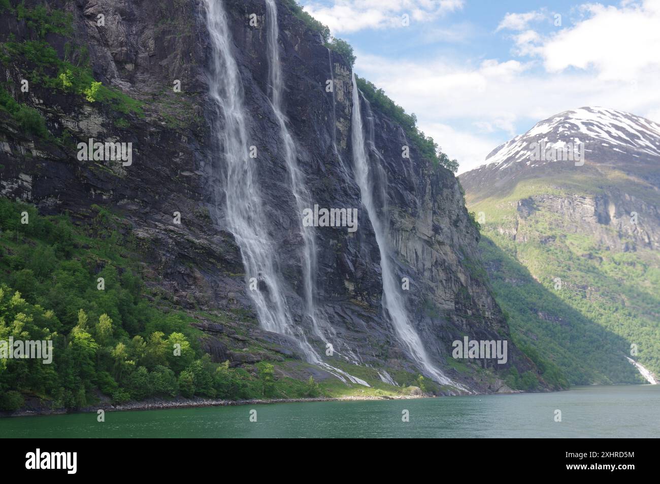 High waterfalls flow down a steep cliff face, surrounded by green ...
