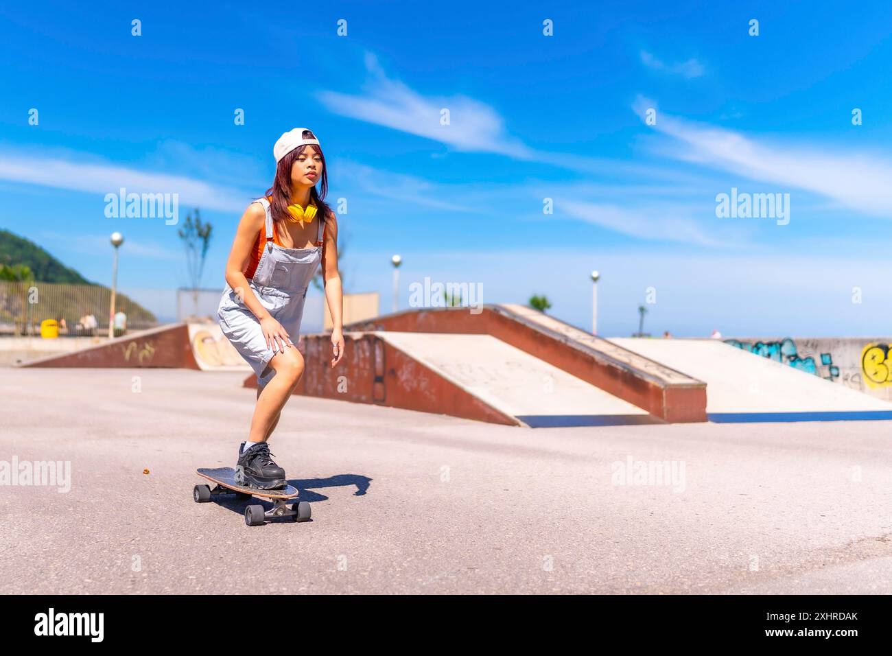 Full length photo of a young female cool asian skater practicing in an ...