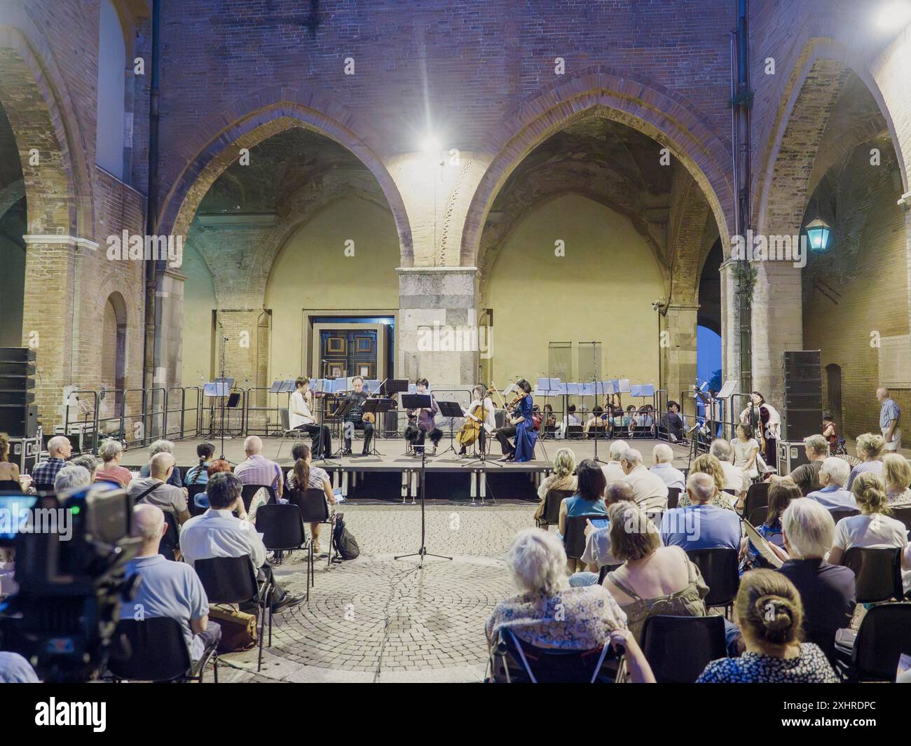 A concert held under archways features musicians performing classical ...