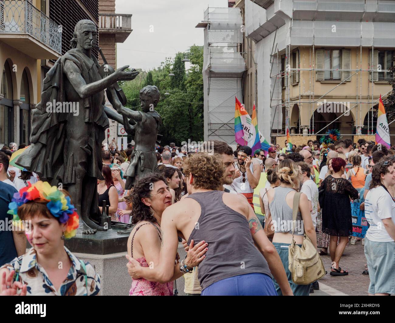 Crowd gathered around a statue with pride flags during an outdoor event ...