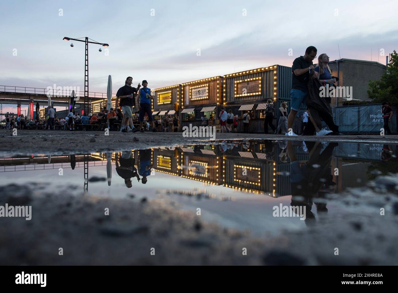 Food stalls are reflected in a puddle at the Melt Festival in ...