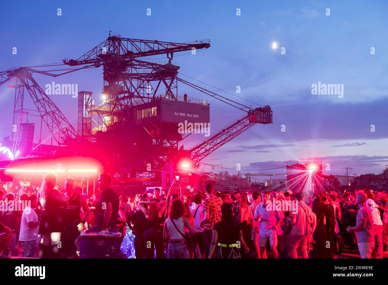 Festival visitors celebrate between excavators at the Melt Festival in ...