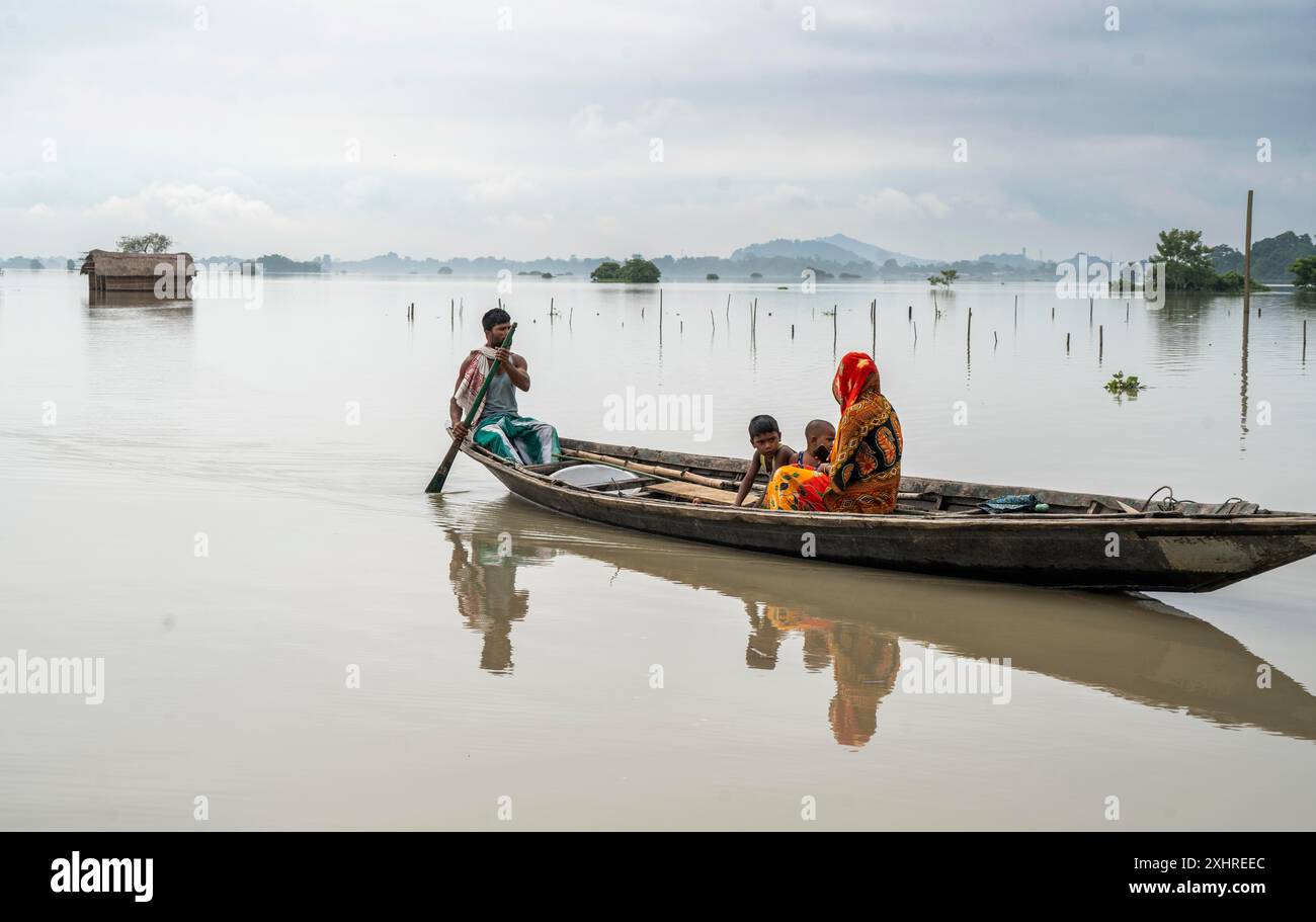 Morigaon, India. 4 July 2024. People travel in a boat to cross a ...